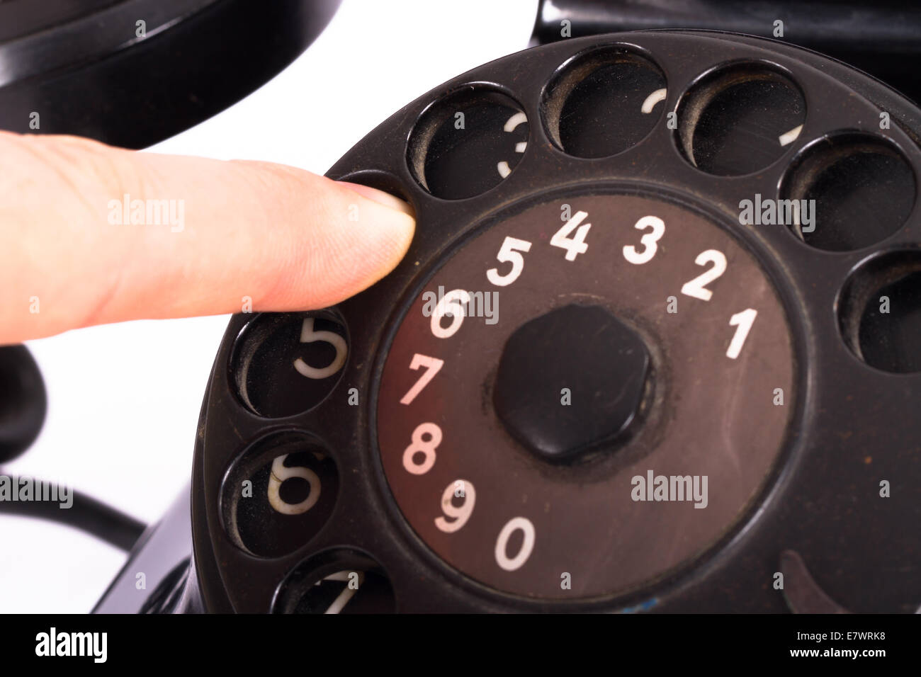 Close up view, hand finger on rotary dial of black vintage phone ...