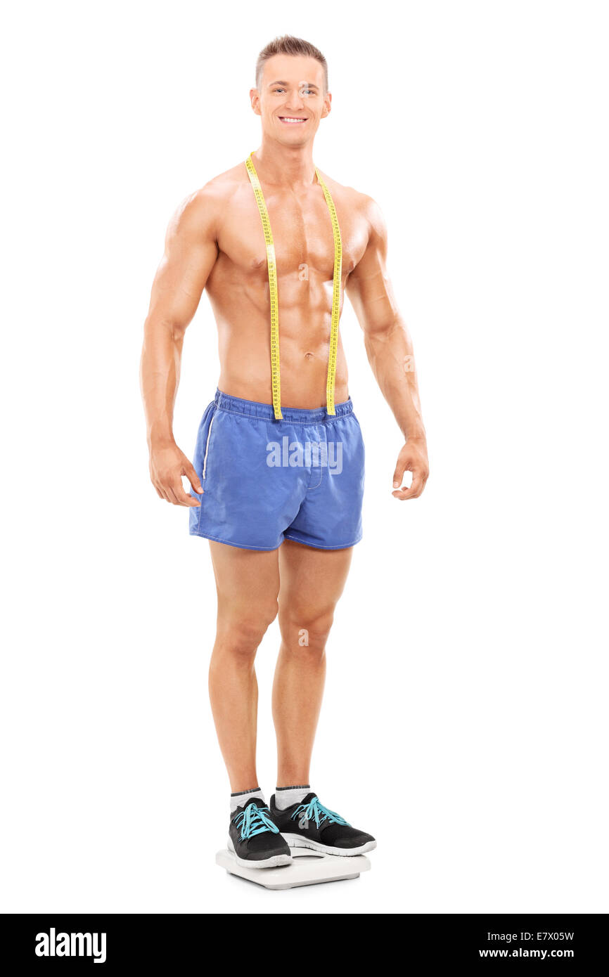 Full length portrait of a handsome man standing on a weight scale ...