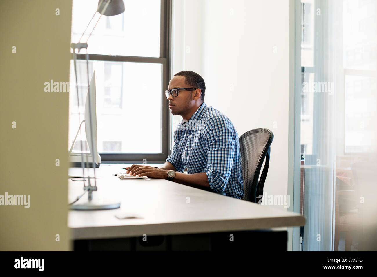 Office life. A man seated at a desk, using a computer screen Stock ...