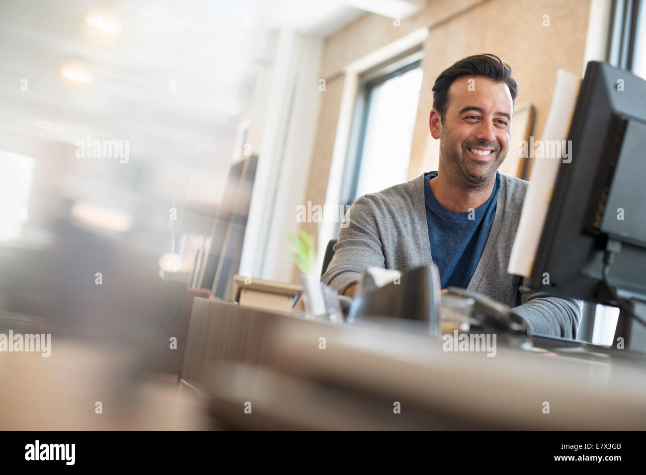 Office life. A man seated at a desk using a computer Stock Photo - Alamy