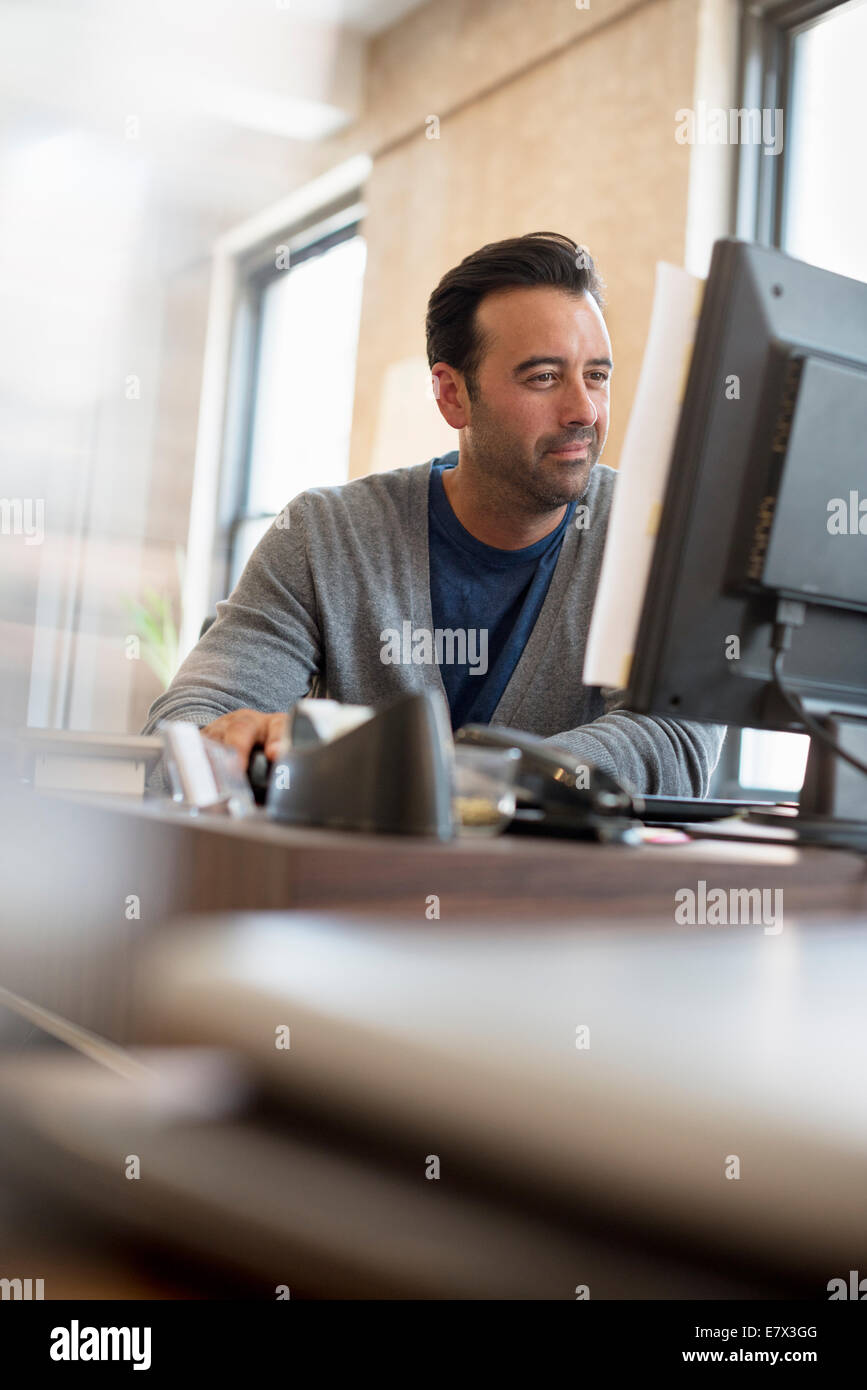 Office life. A man seated at a desk using a computer Stock Photo - Alamy
