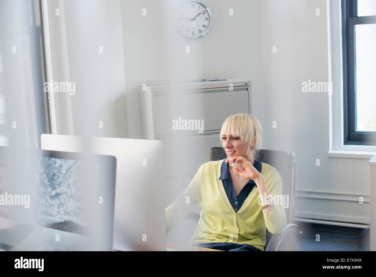 A woman seated at an office desk using a computer Stock Photo - Alamy