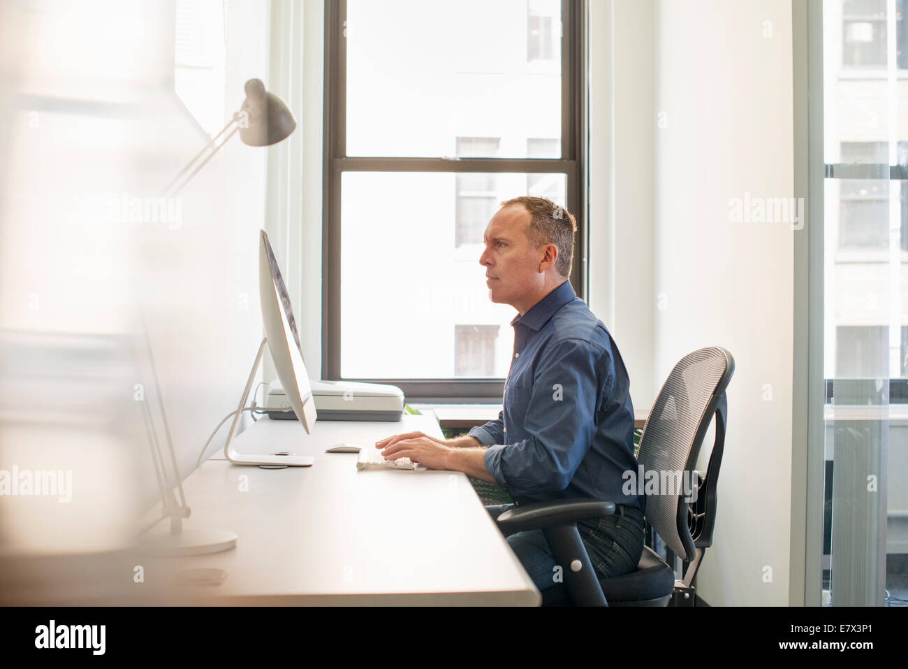 A businessman seated at his desk working at a computer Stock Photo - Alamy