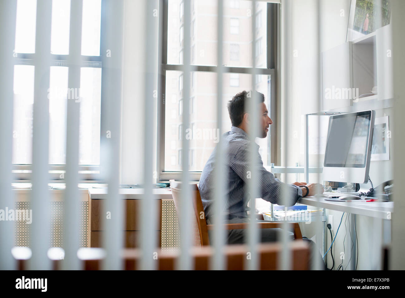 Office life. A man sitting at a desk using a computer, looking intently ...