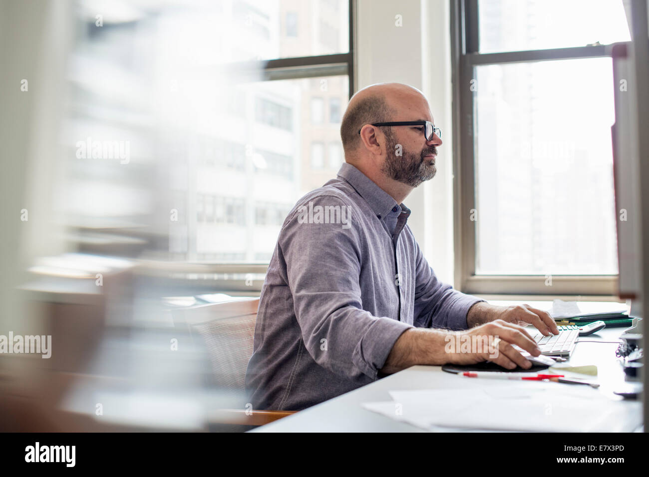 Office life. A man sitting at a desk using a computer, looking intently ...