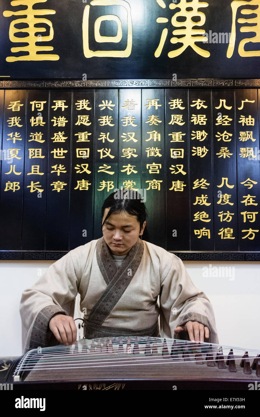 Man wearing traditional Manchurian dress playing zheng, a plucked ...