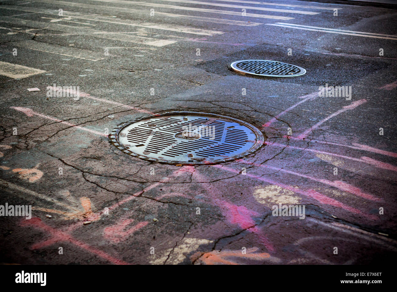 A manhole cover surrounded by various markings delineating below ground ...
