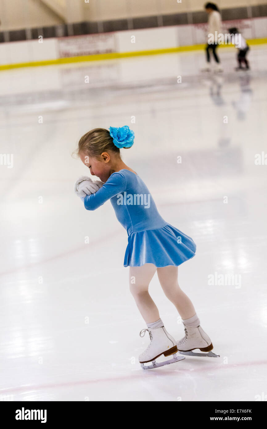 Cute young girl practicing figure skating on indoor ice skating rink ...