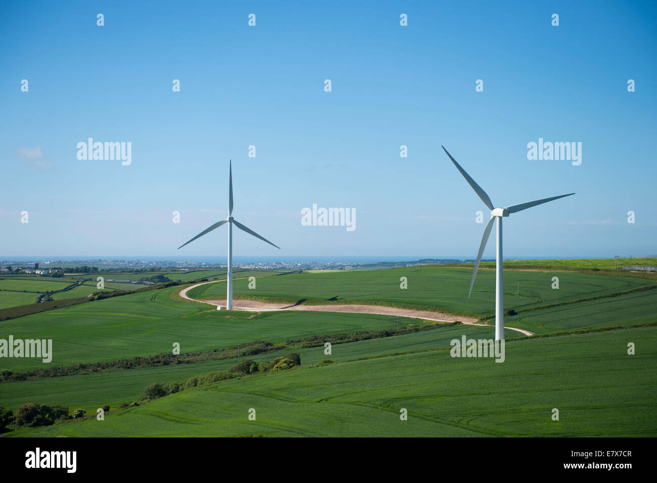Wind turbines producing renewable green energy on a green hill with a ...