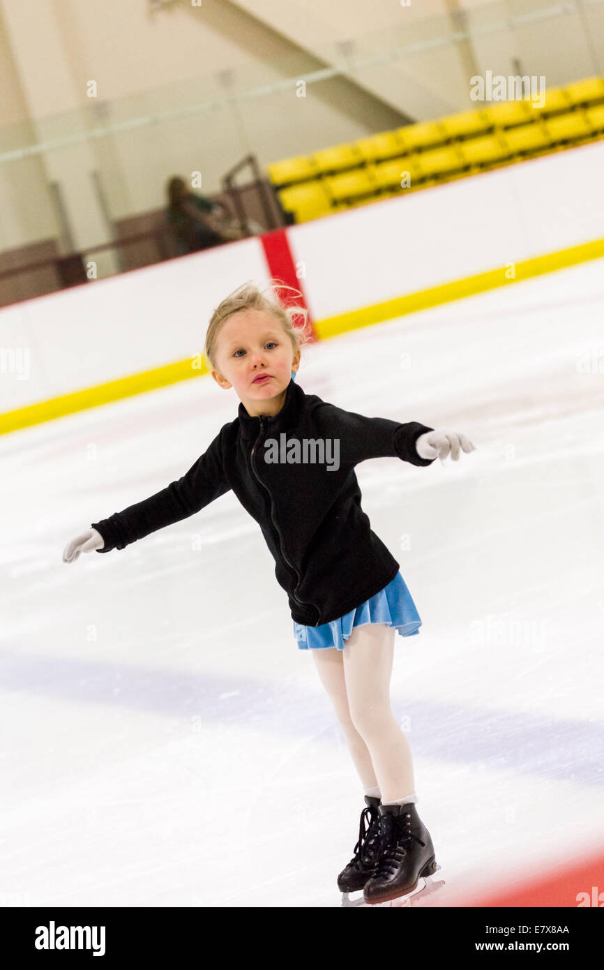 Cute young girl practicing figure skating on indoor ice skating rink ...