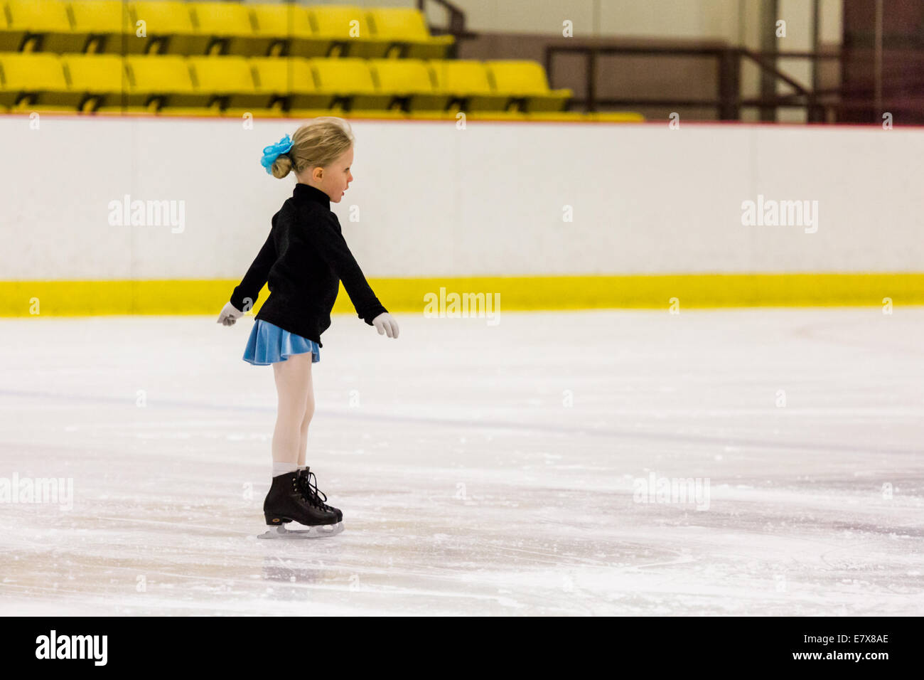 Cute young girl practicing figure skating on indoor ice skating rink ...