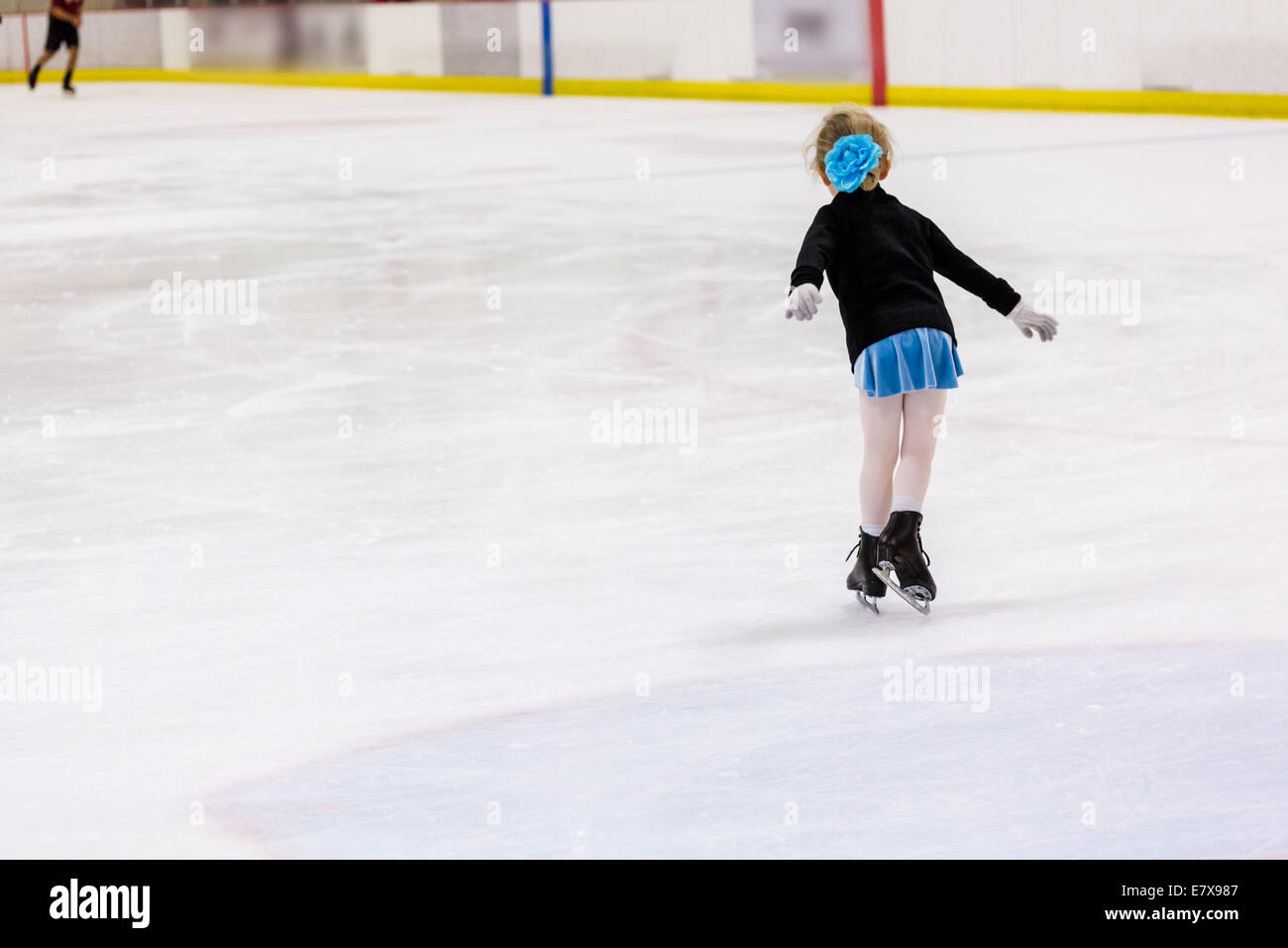 Cute young girl practicing figure skating on indoor ice skating rink ...