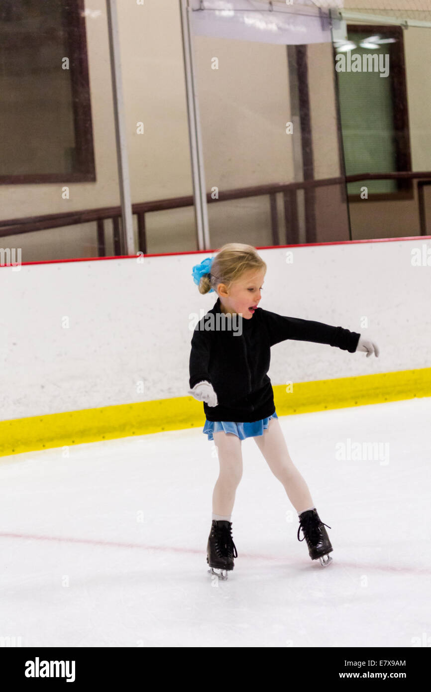 Cute young girl practicing figure skating on indoor ice skating rink ...