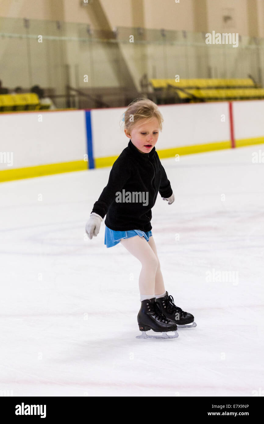 Cute young girl practicing figure skating on indoor ice skating rink ...