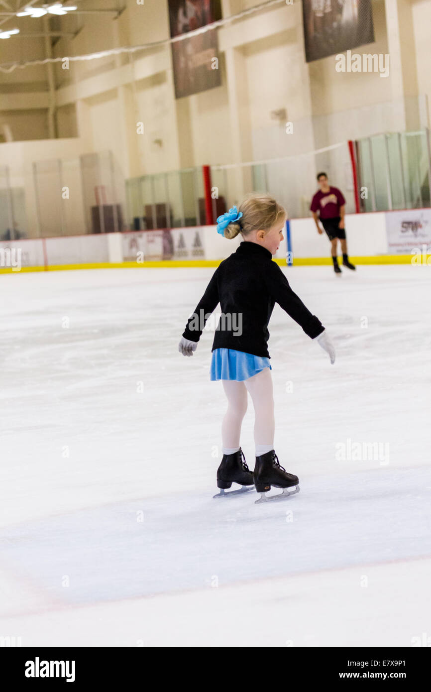 Cute young girl practicing figure skating on indoor ice skating rink ...
