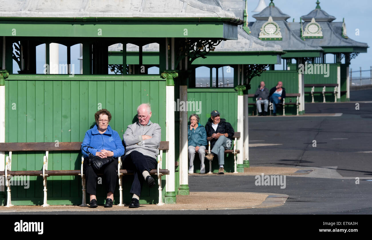 Older couples sitting on benches in a row of shelters on Blackpool ...
