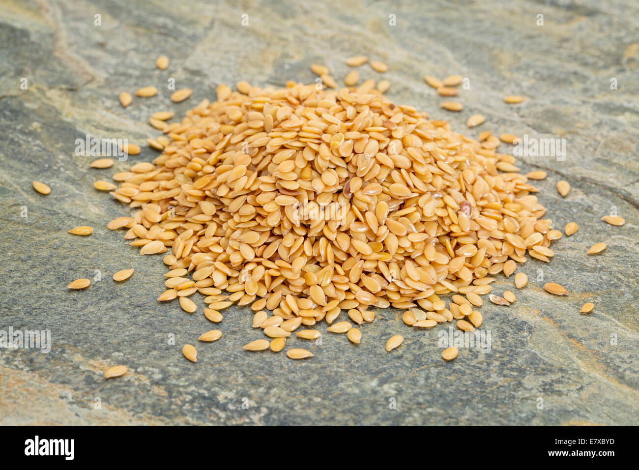 heap of gold flax seeds against slate rock background Stock Photo - Alamy