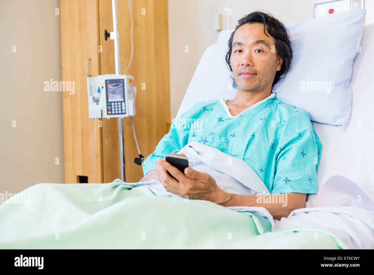 Patient Holding Mobile Phone While Resting On Hospital Bed Stock Photo ...