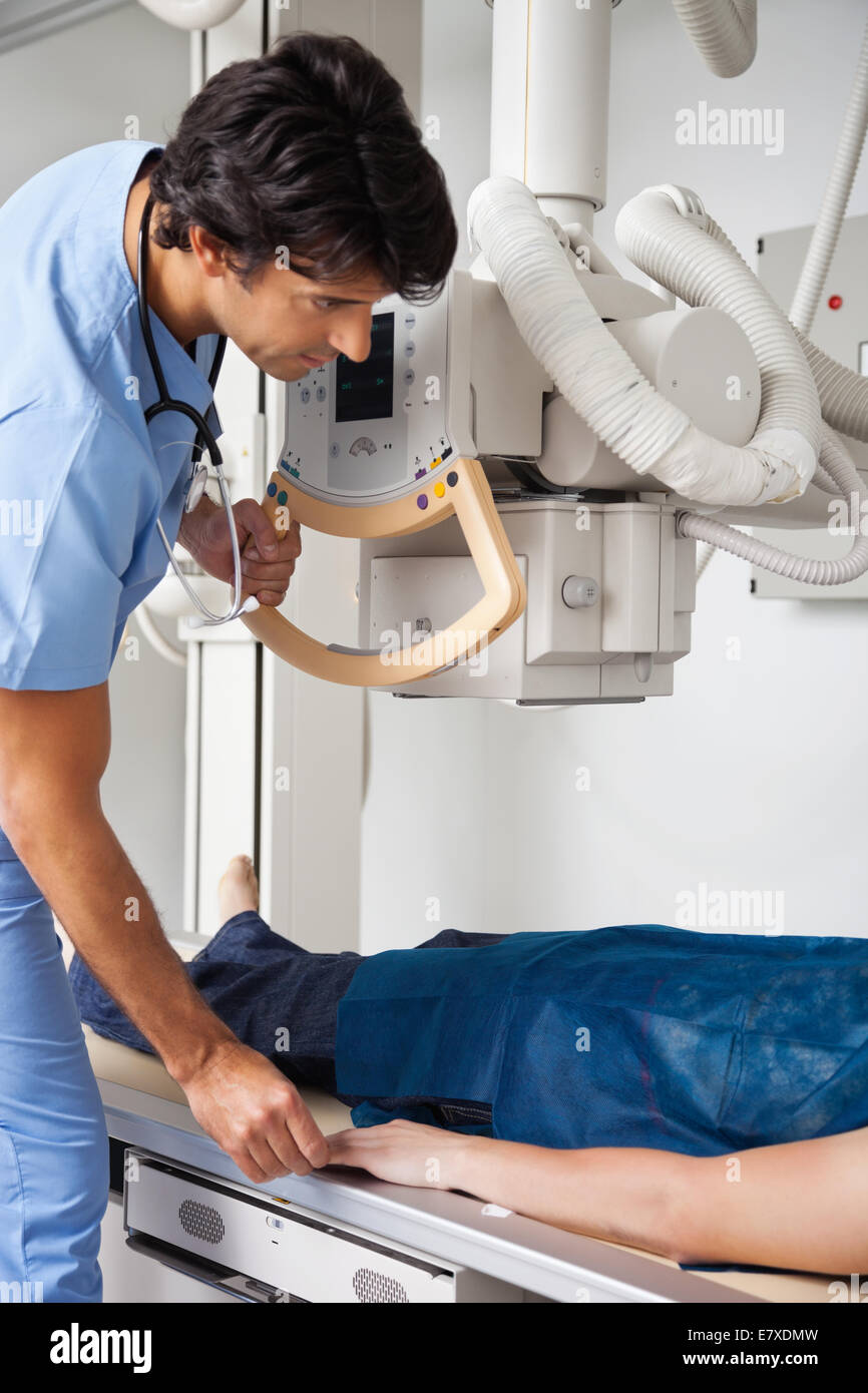 Mixed race male technician setting up machine to take patient's x-ray ...