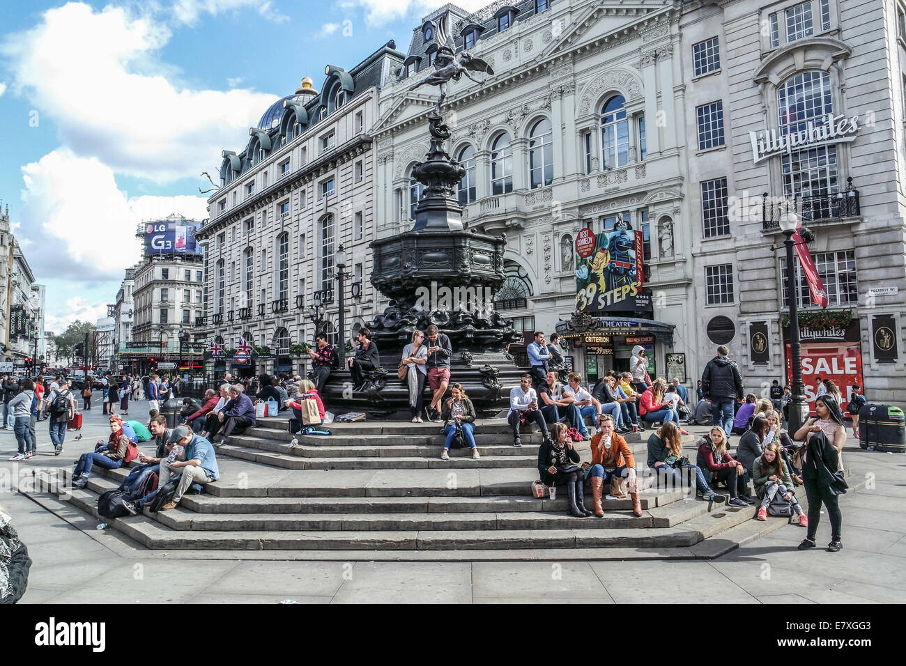 Piccadilly Circus,London, Tourists sit on the Steps of the Eros Statue ...