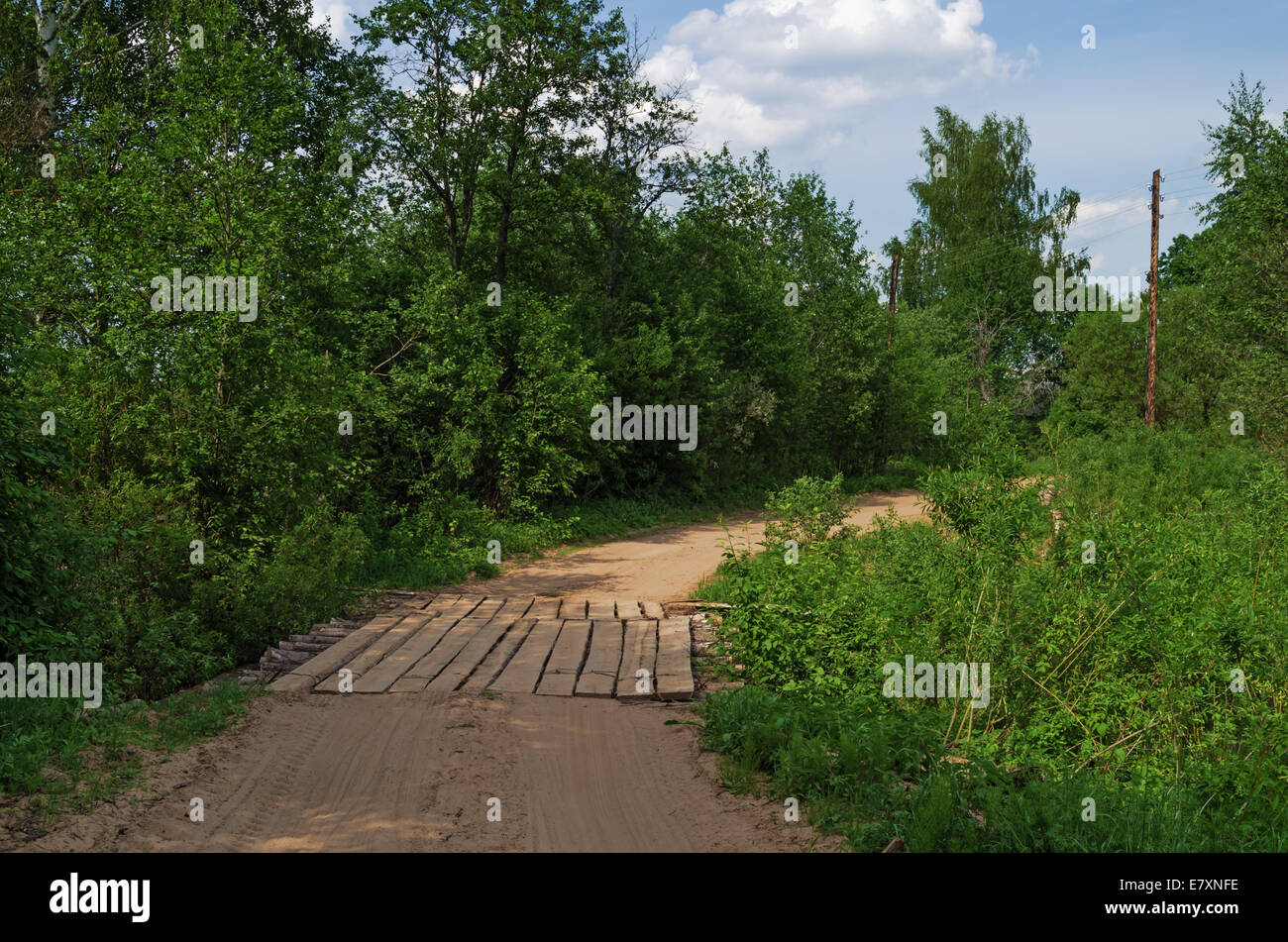 Village sand road. Wooden bridge over small river Stock Photo - Alamy