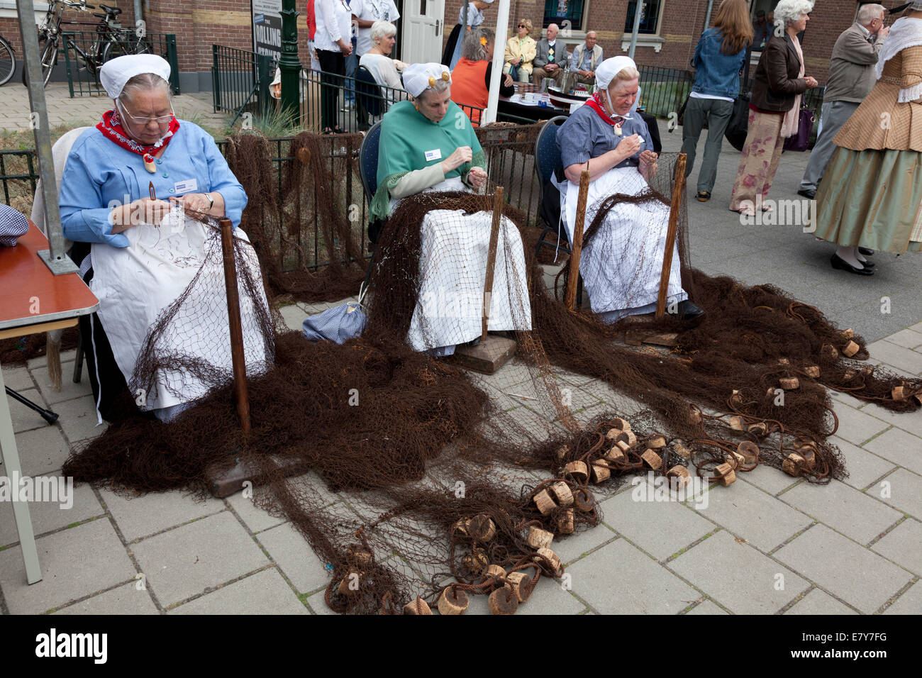 Woman in traditional costumes from Scheveningen finding fishing nets ...