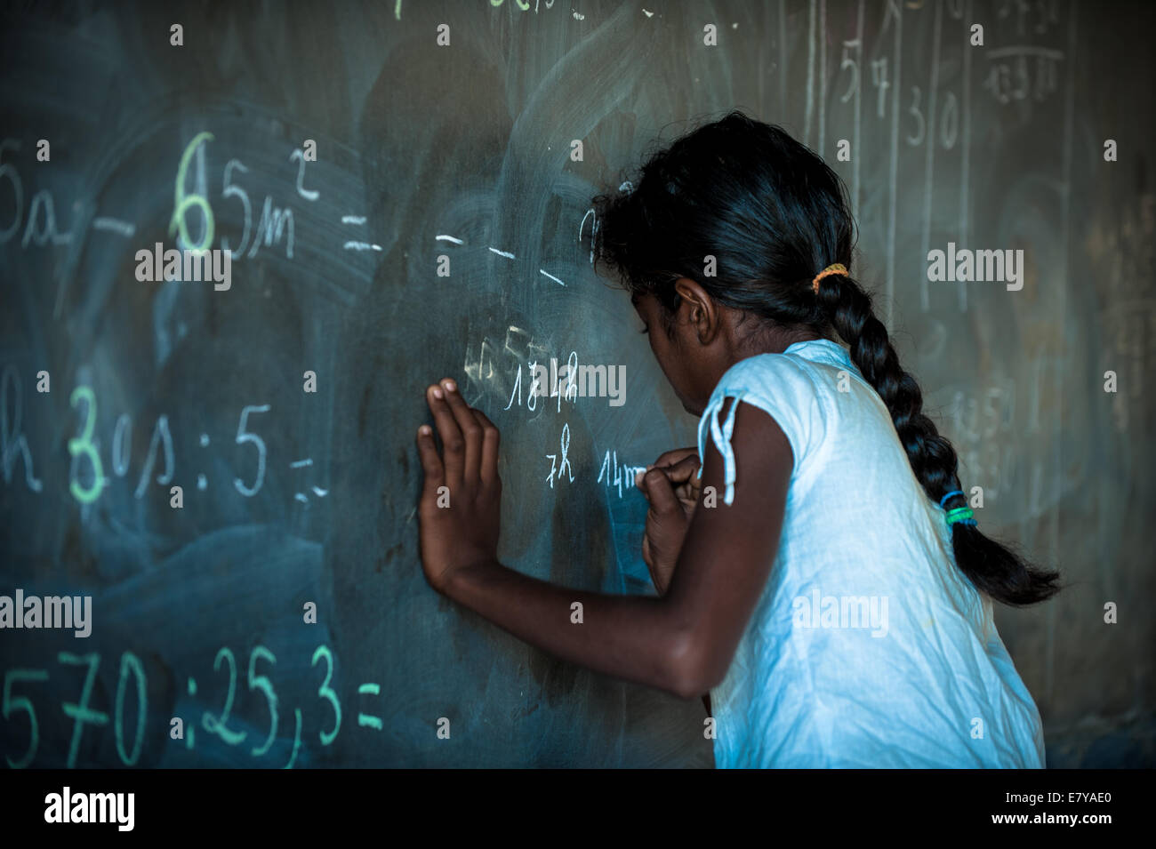 A young girl writes on a blackboard in a classroom. Hell Ville school ...
