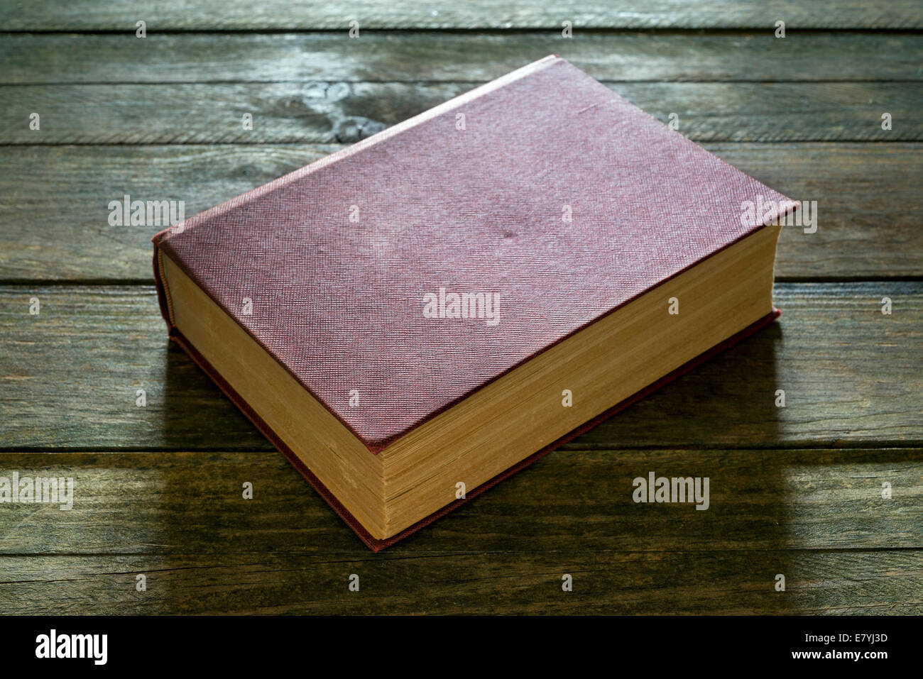 An old red book on a wooden table Stock Photo - Alamy