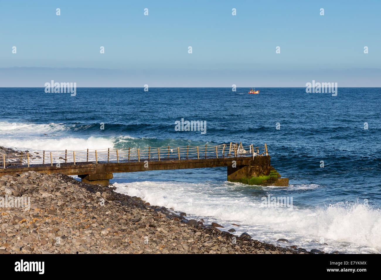 Coast Madeira with concrete jetty and small fishing ship at sea Stock ...