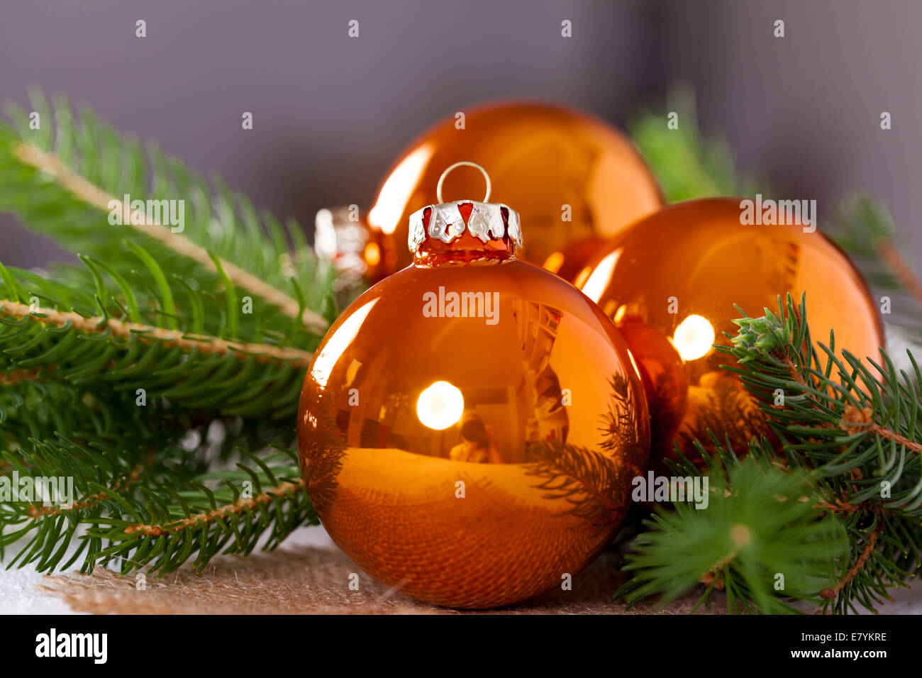 Shiny bright copper colored Christmas balls nestling in a branch of ...