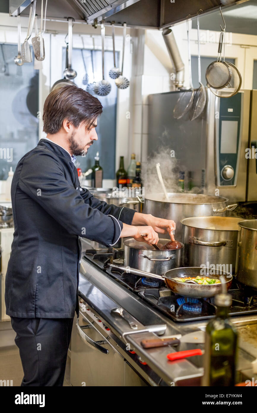 Professional chef in a commercial kitchen cooking a vegetable stir fry ...