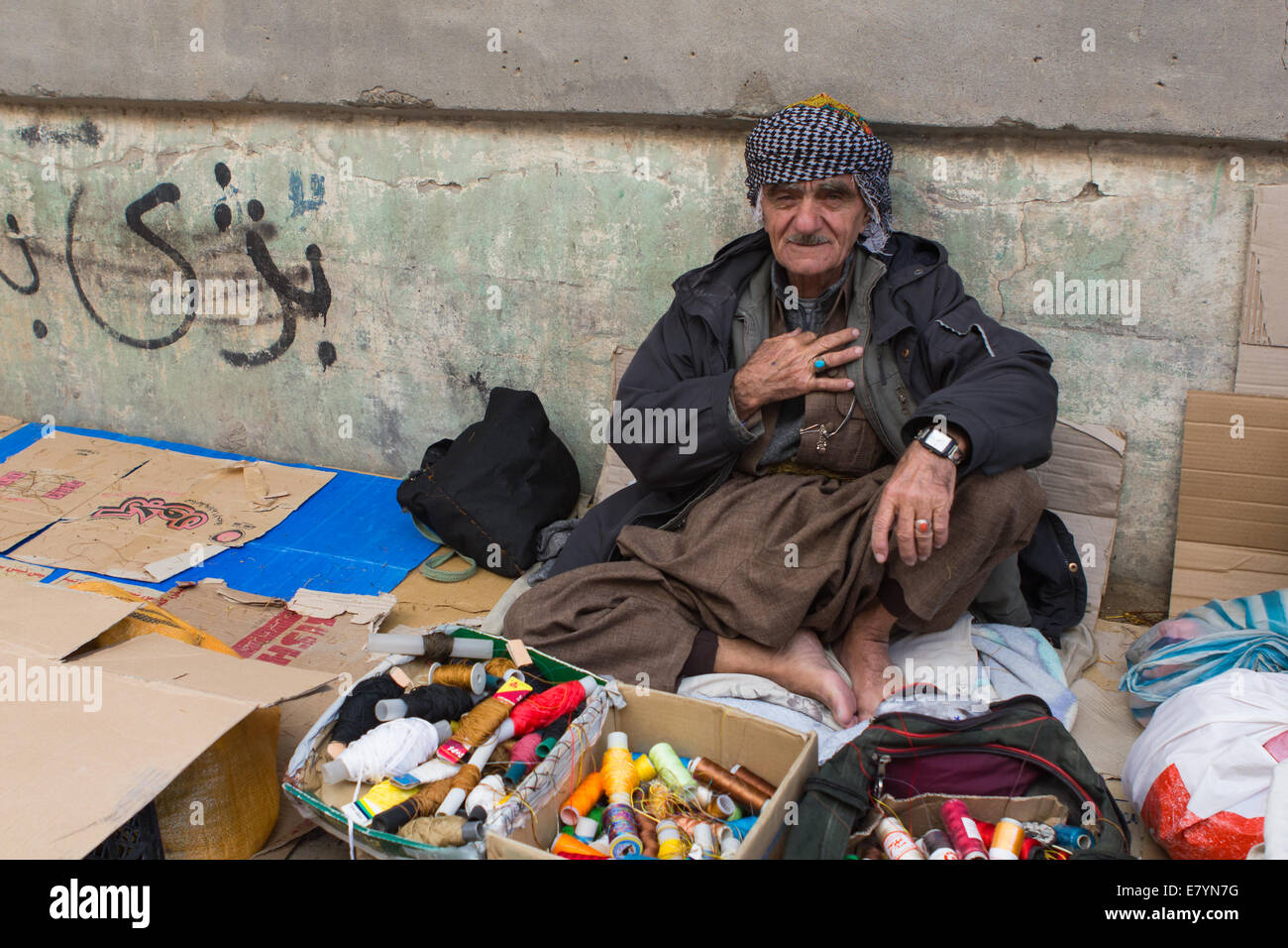 A Kurdish street vendor wearing traditional clothing selling yarn and ...