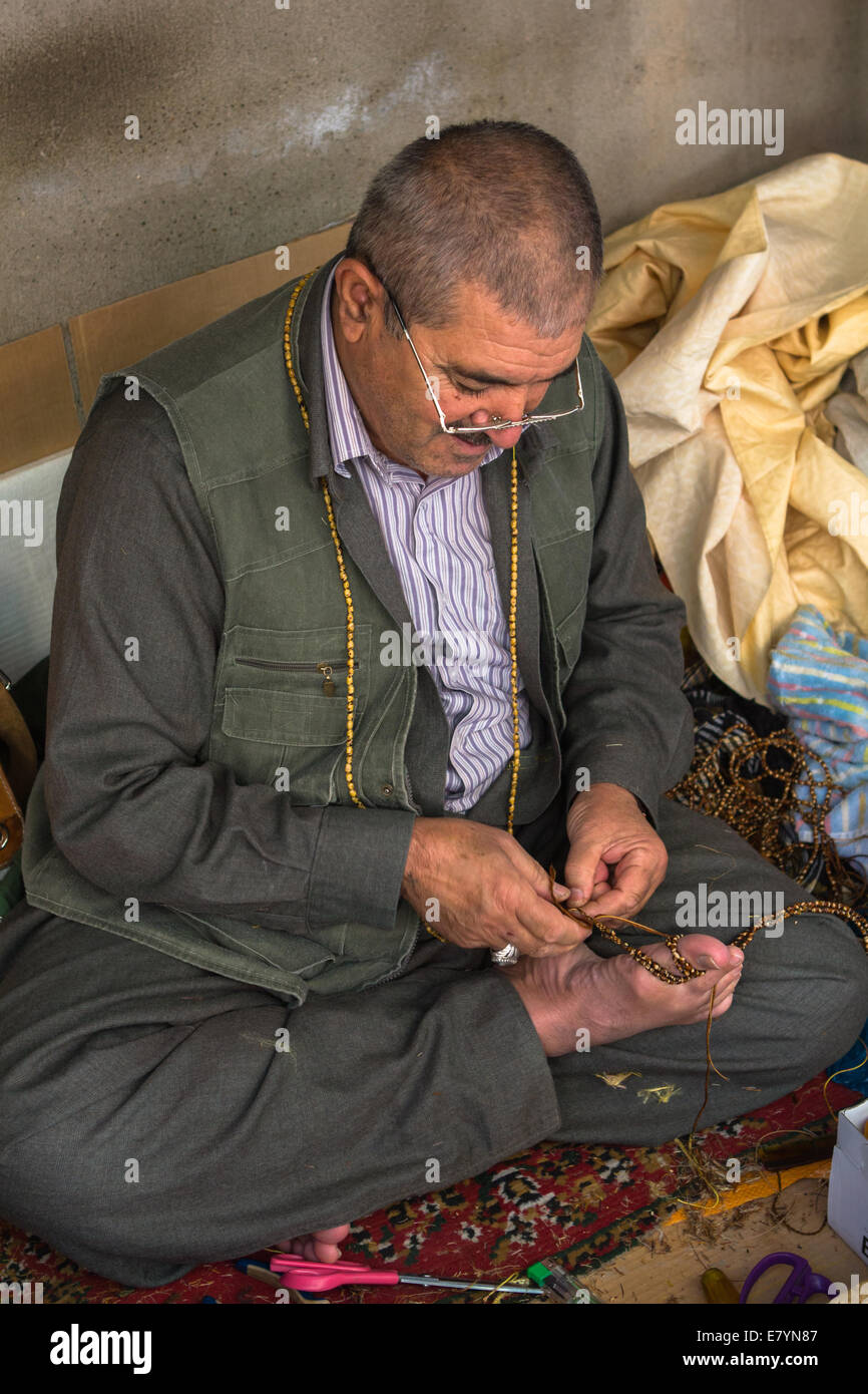 A Kurdish street vendor wearing traditional clothing making prayer ...