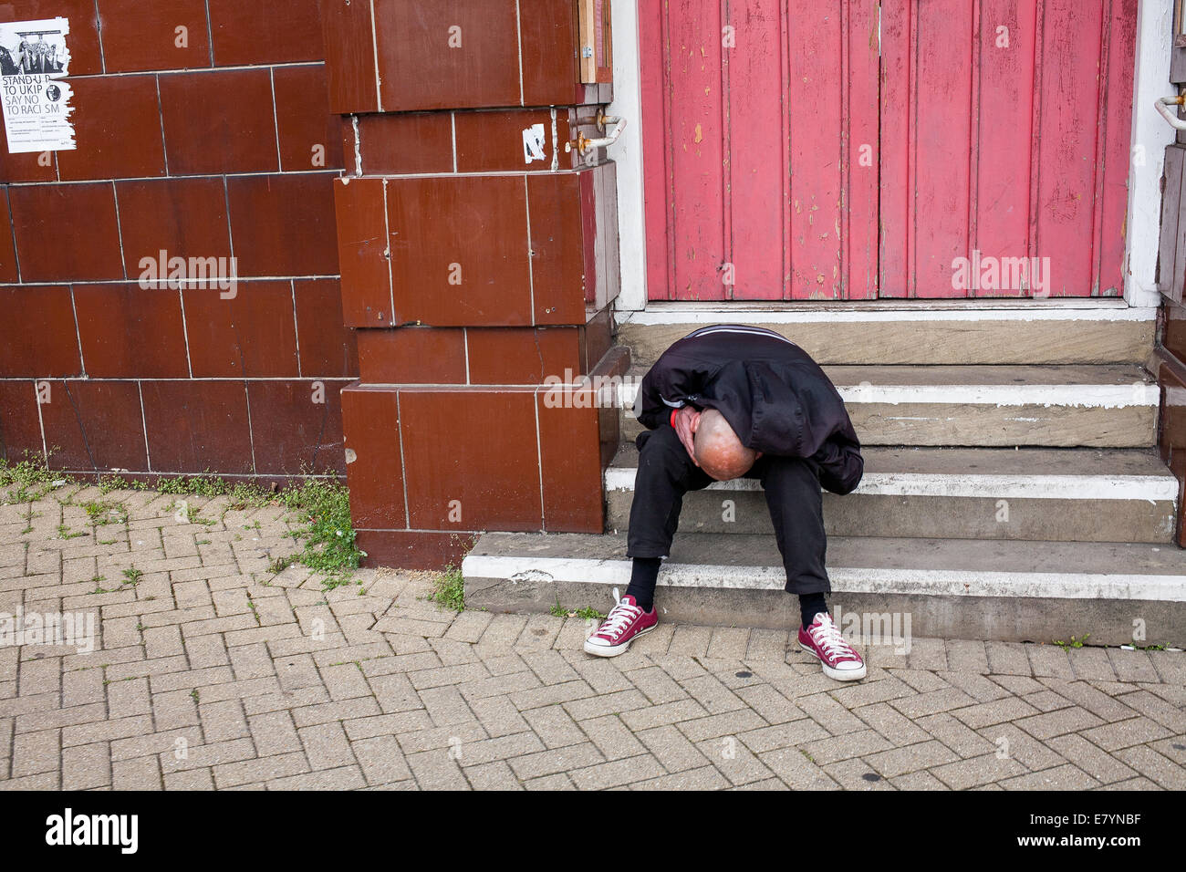 A man sits outside a pub with his head in his hands Stock Photo - Alamy