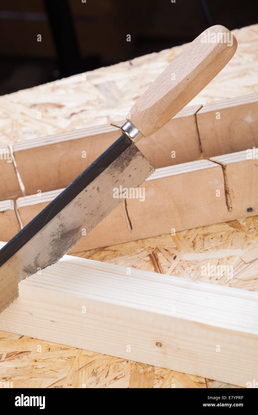 Toothed steel hand saw cutting through a new beam of wood left in ...