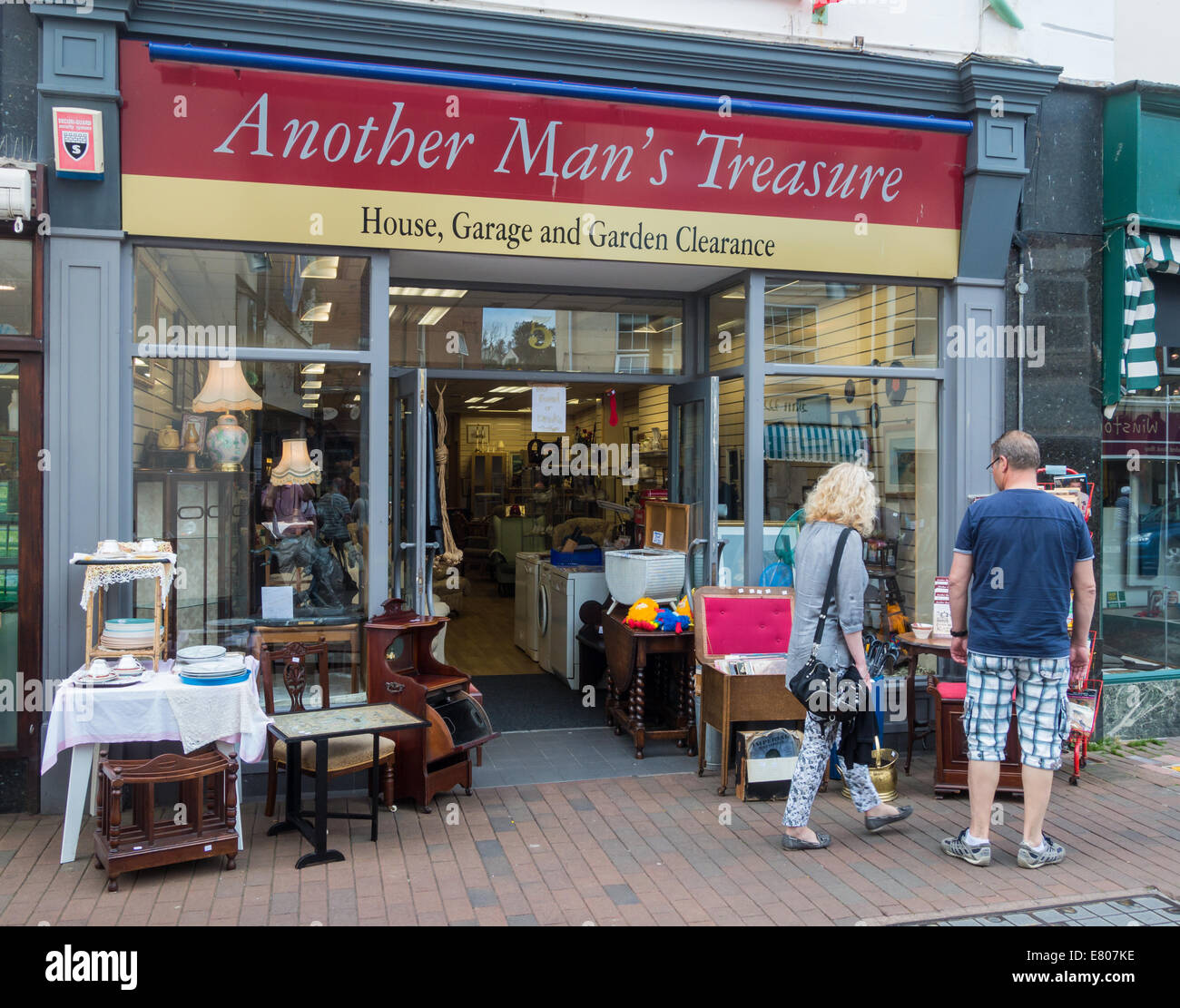 Sidmouth, Devon, England. An adult couple inspecting items for sale ...