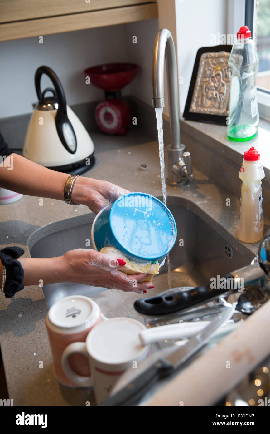 young woman washing up at kitchen sink after baking Stock Photo - Alamy