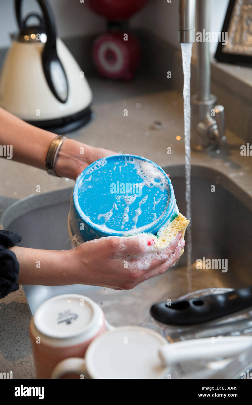 young woman washing up at kitchen sink after baking Stock Photo - Alamy