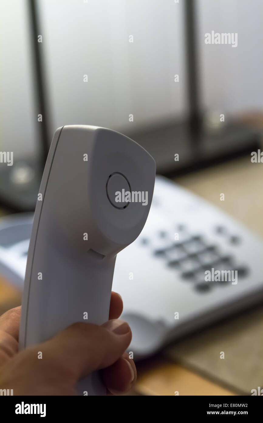Hand holding white telephone tube in hotel room Stock Photo - Alamy