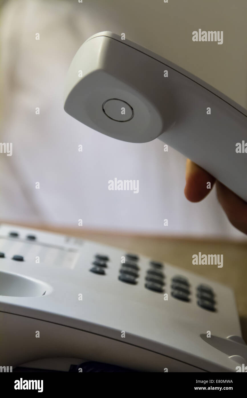 Hand holding white telephone tube in hotel room Stock Photo - Alamy