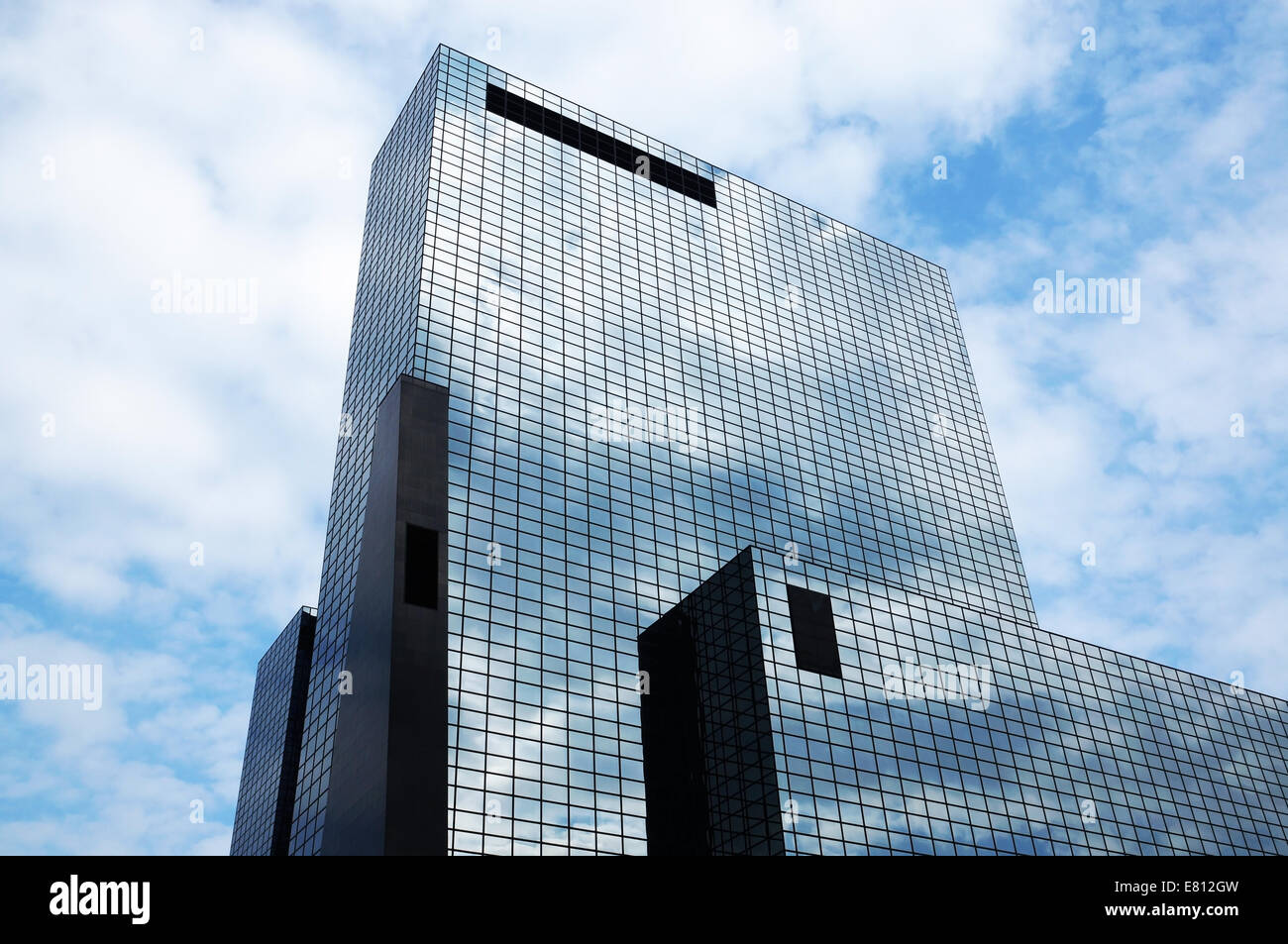generic office building with glass facade reflecting sky and clouds ...