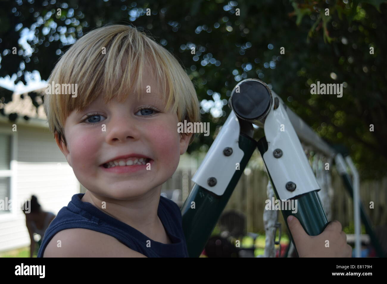 Smiling boy atop swing set playing outside Stock Photo - Alamy