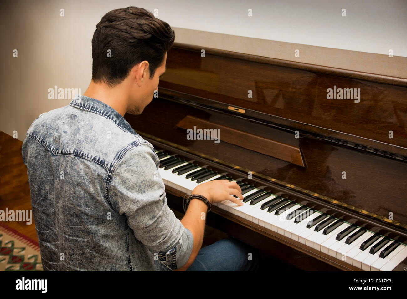 Young handsome male artist playing his wooden classical upright piano ...