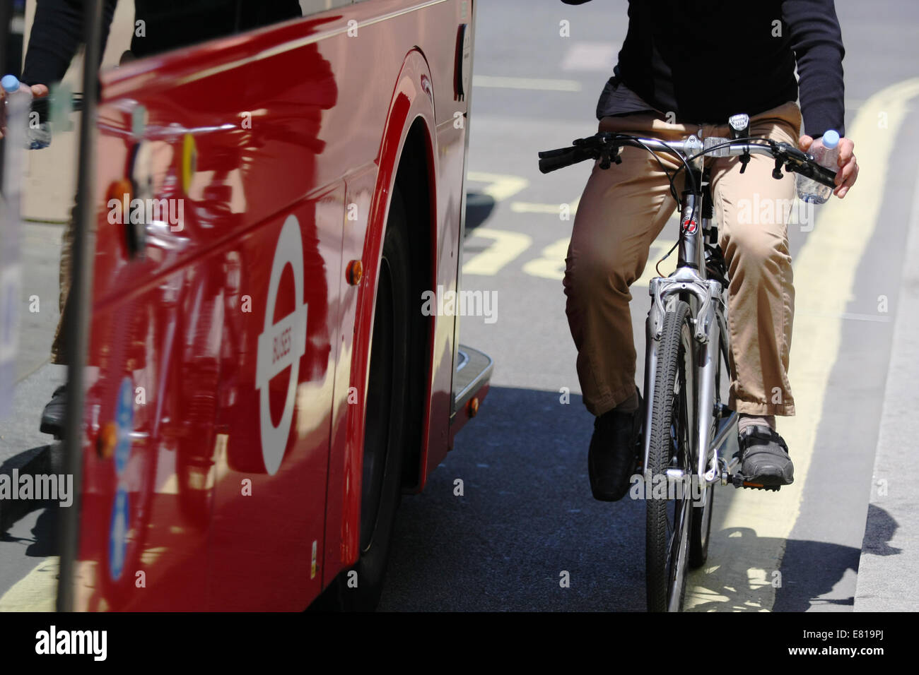 A cyclist riding between a bus and pavement in London Stock Photo - Alamy