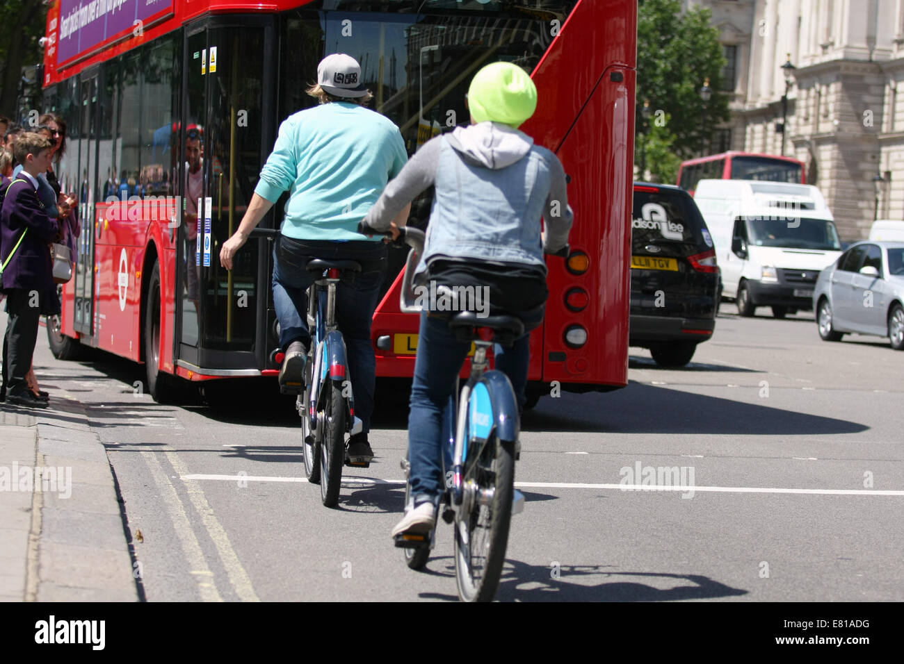 Two cyclists riding behind a red London bus Stock Photo - Alamy