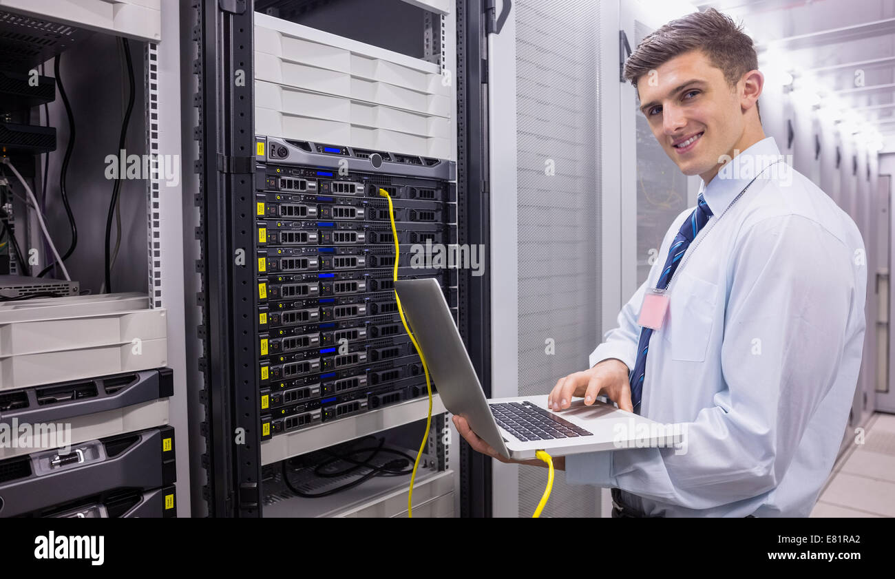 Smiling technician using laptop while analysing server Stock Photo - Alamy