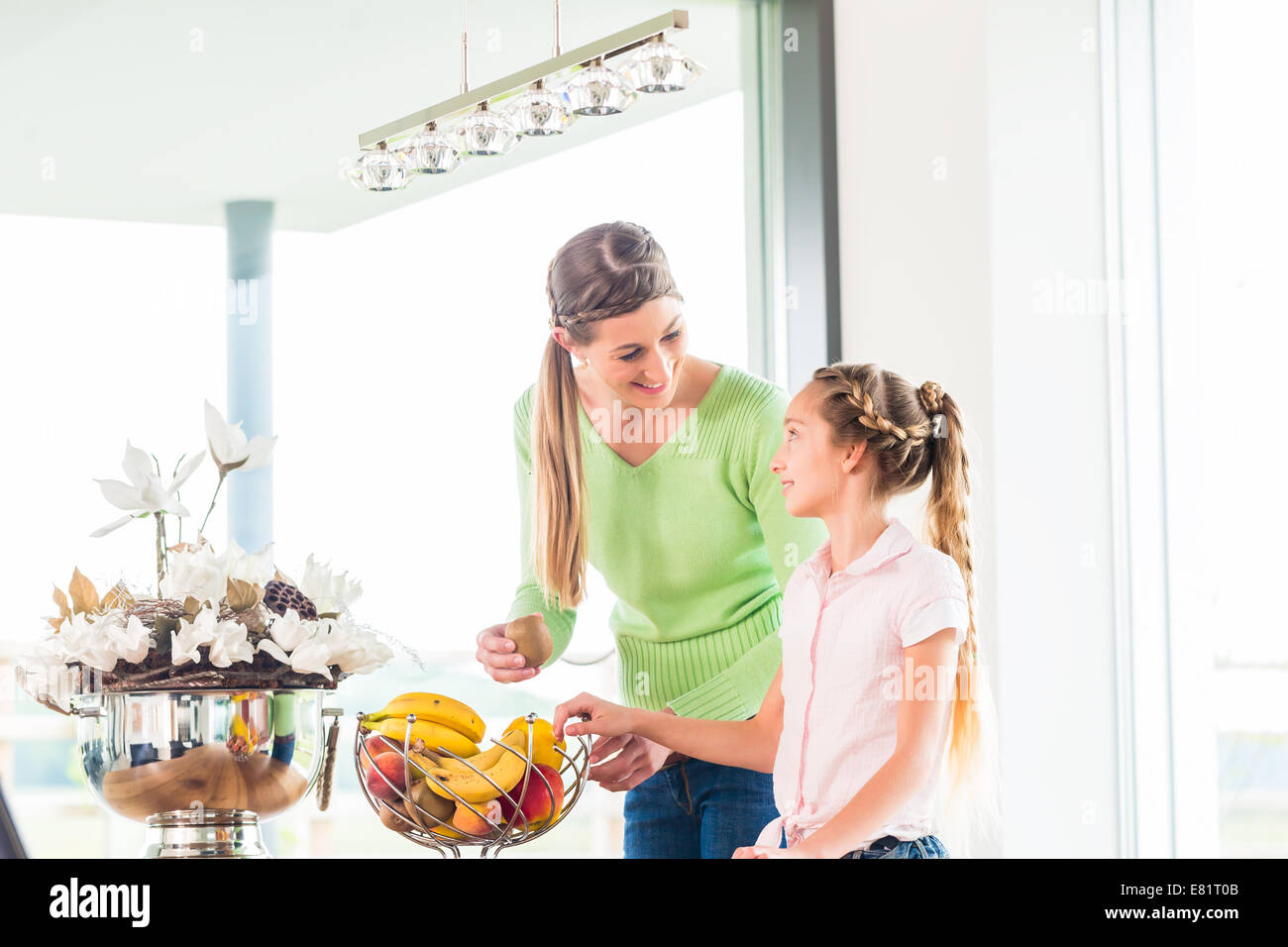 Mother giving child fresh fruits for healthy living in home kitchen ...
