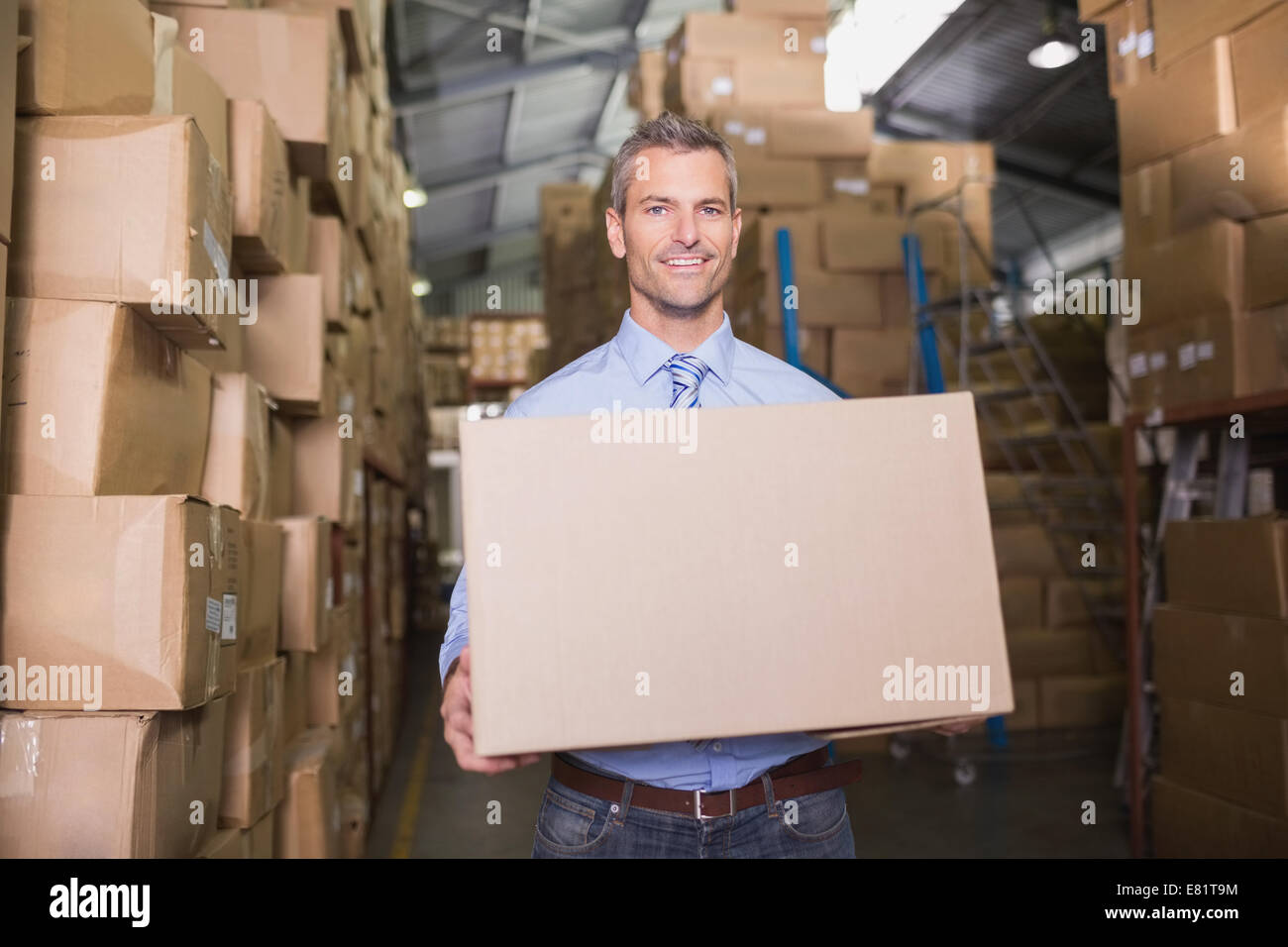 Worker carrying box in warehouse Stock Photo - Alamy