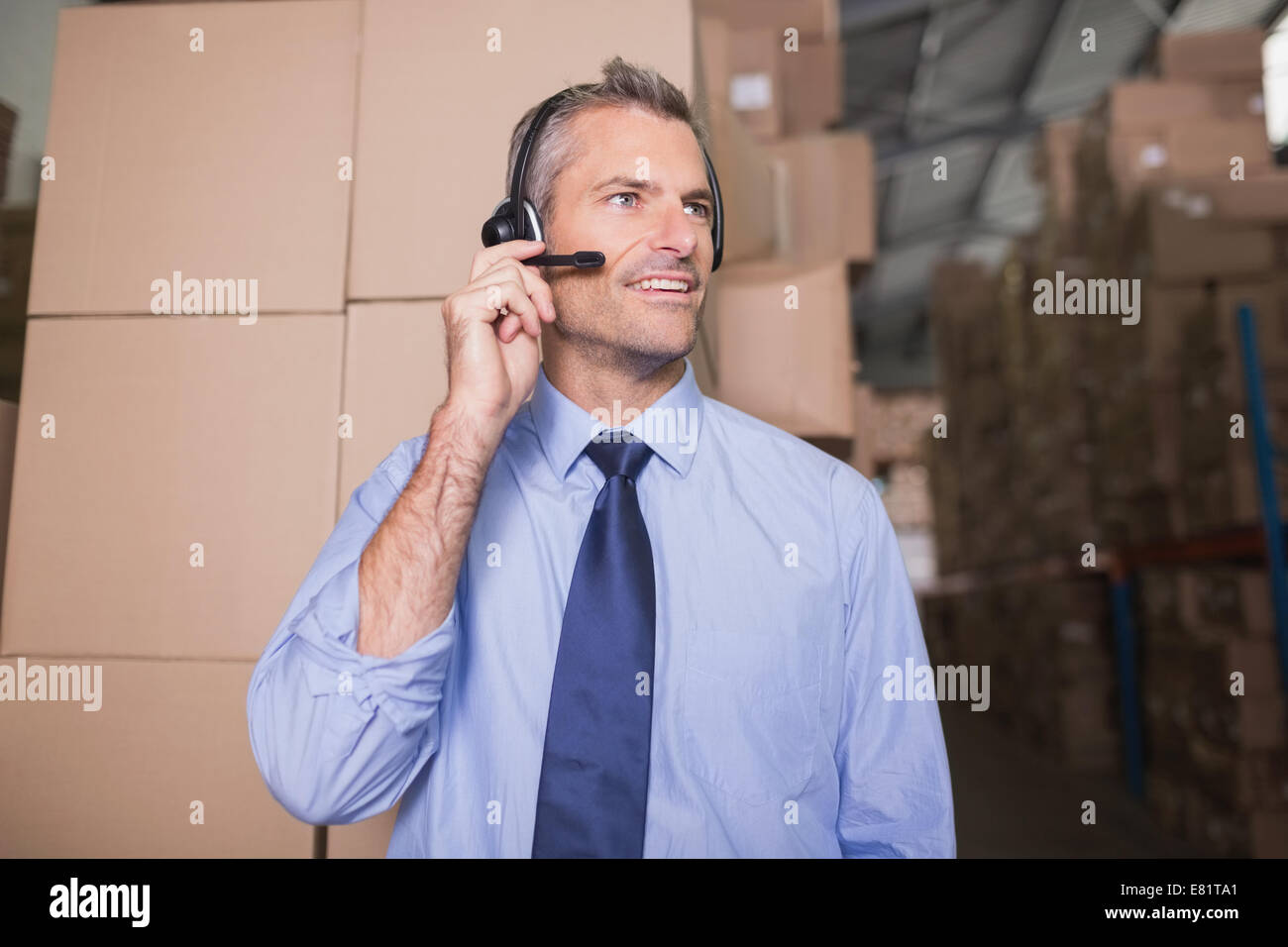 Businessman using headset in warehouse Stock Photo - Alamy