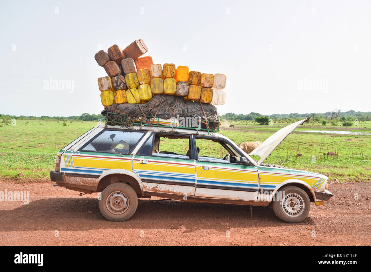 A Peugeot 504 carrying tens of yellow water jerry cans broken down in ...